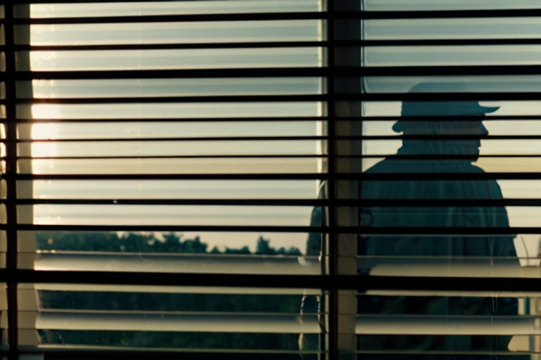 an external straight at camera shot of a residential window, shadowy ...